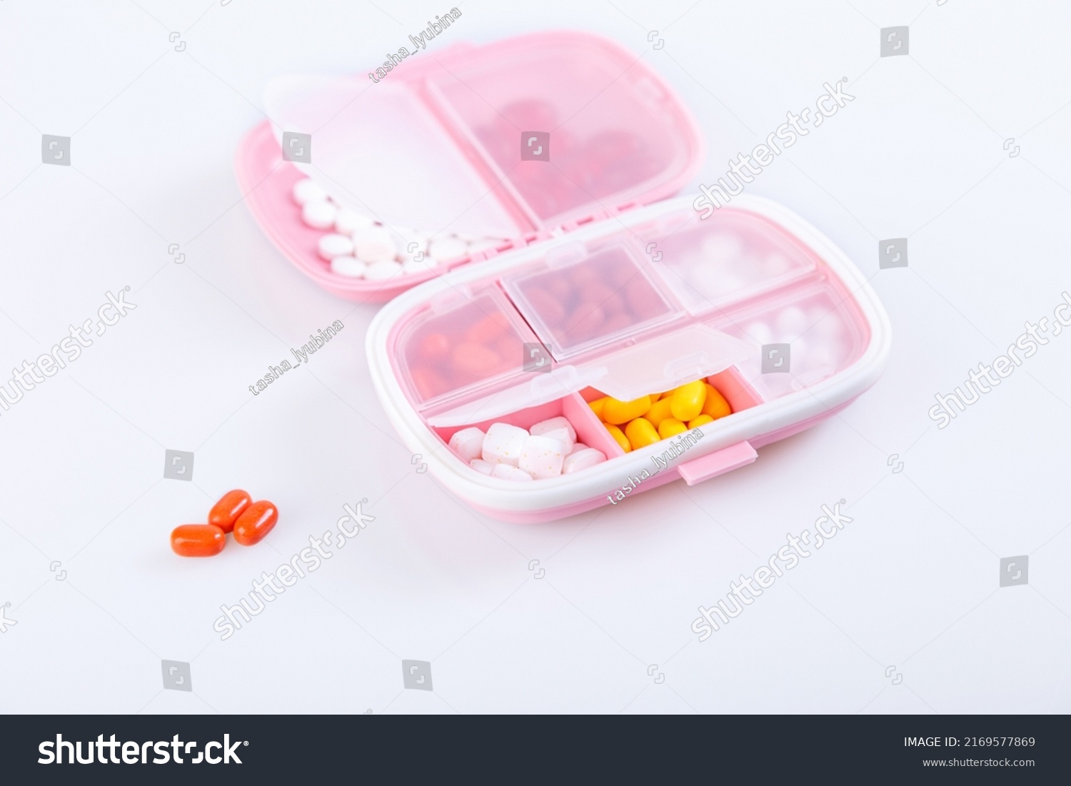 Pill box with colorful pills and vitamins. Plastic pink container with ...