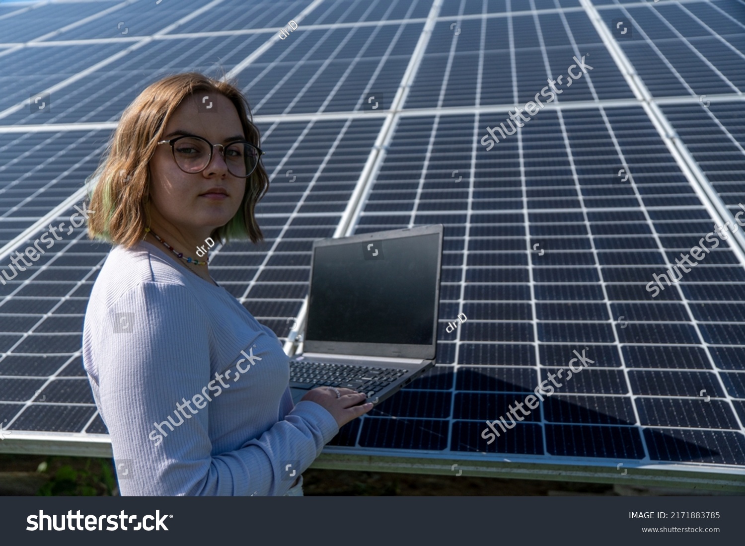 A young female engineer working with solar panels programs and optimizing work of the solar ...