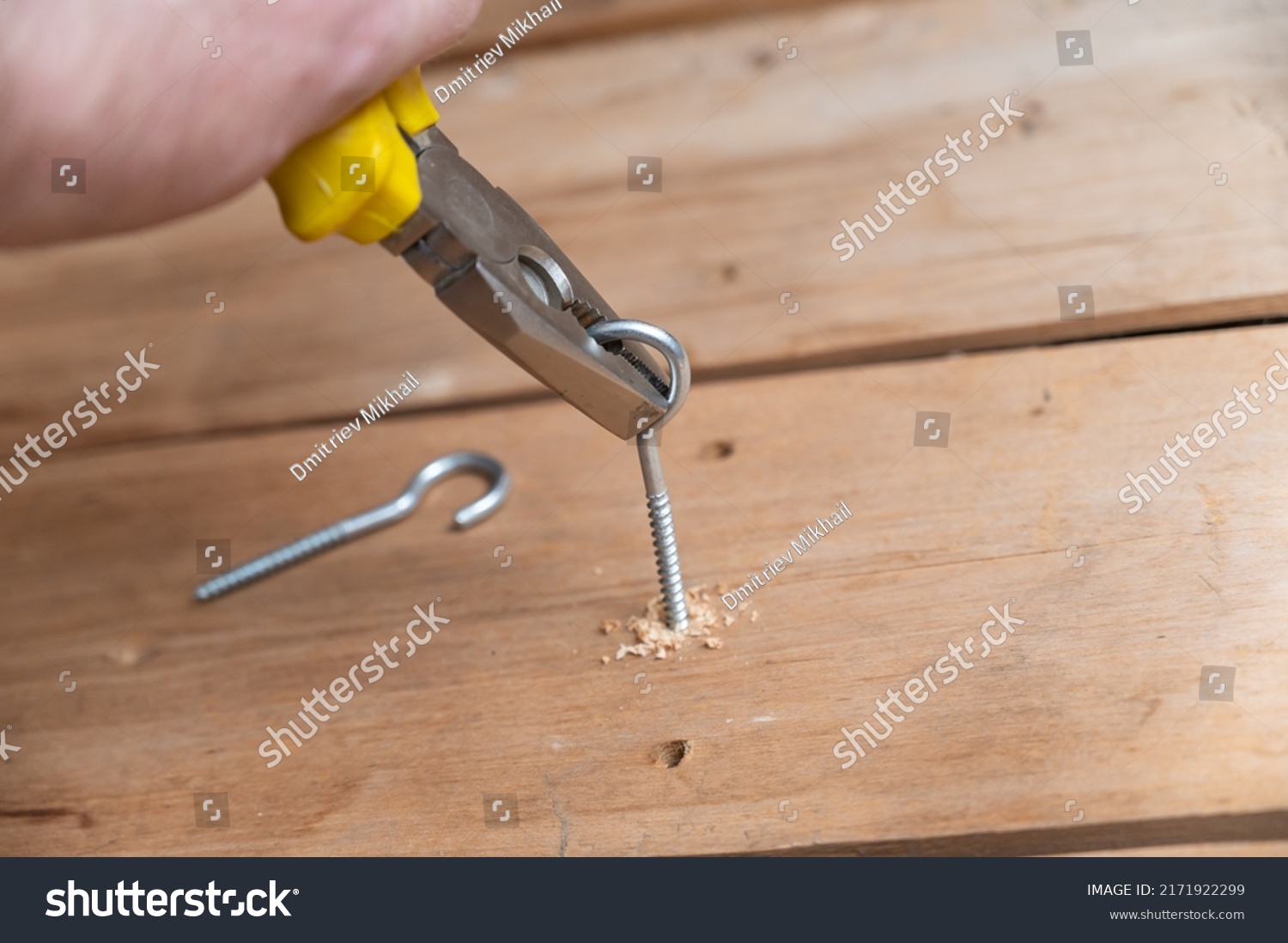 The process of screwing a half-ring screw into a board. The man's hand ...