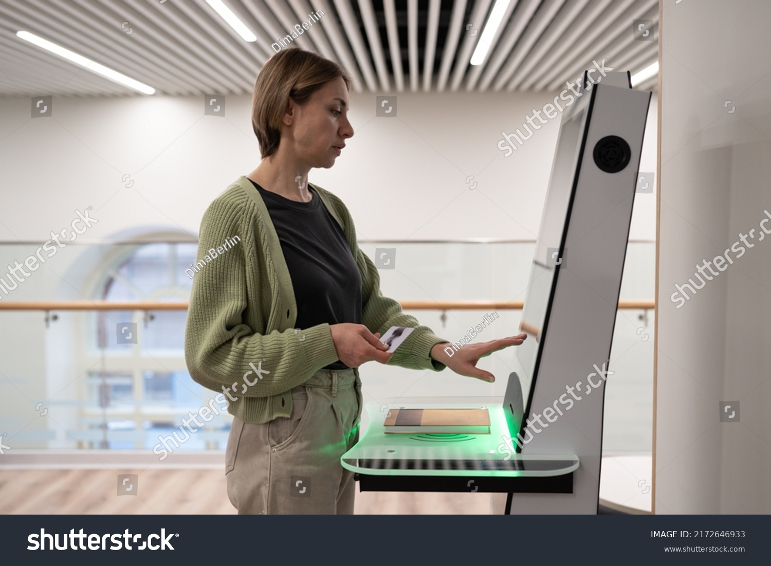 Middle-aged woman using self-service terminal in digital library space ...