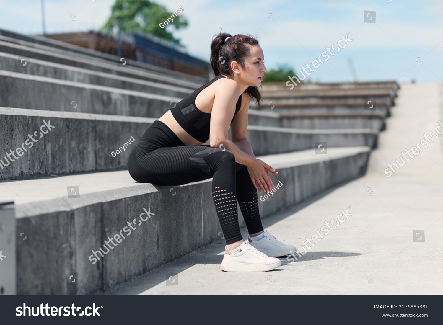 Exhausted young woman after training sitting on stairs at sports ...