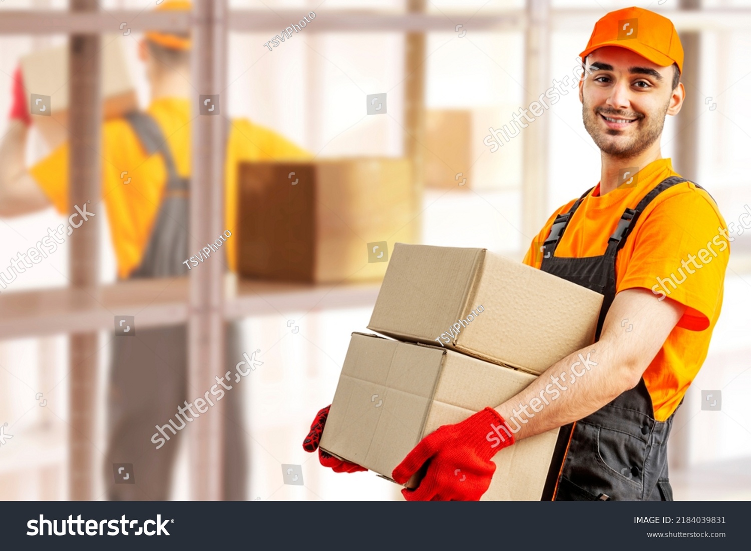 Young man holding cardboard package working in warehouse among racks ...