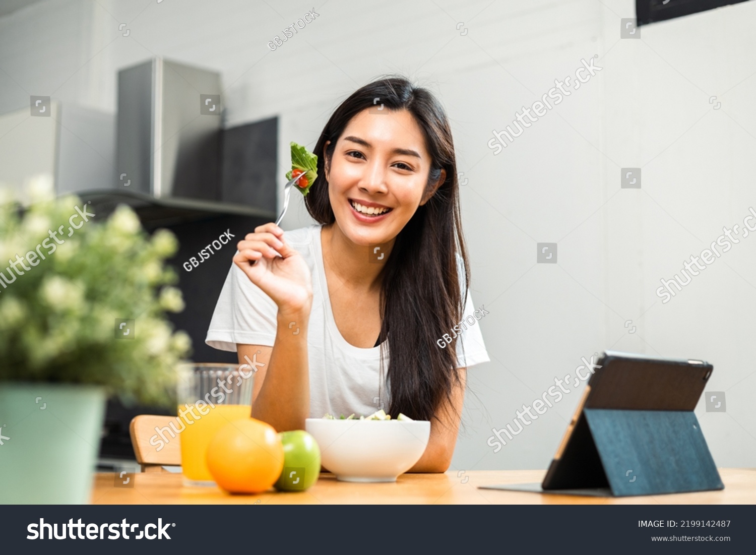 Young female eating organic greens vegetable salad in weight loss diet and wellness on table ...