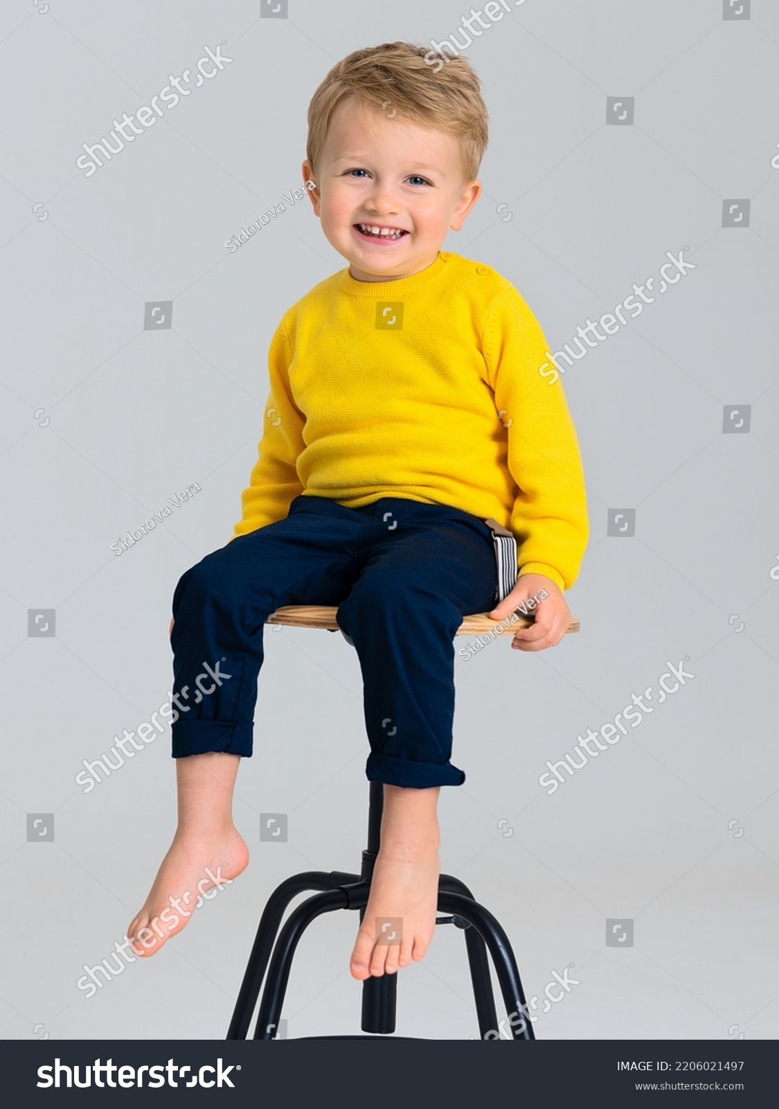 A boy in yellow sits barefoot on a chair and smiles fervently. Tomboy ...