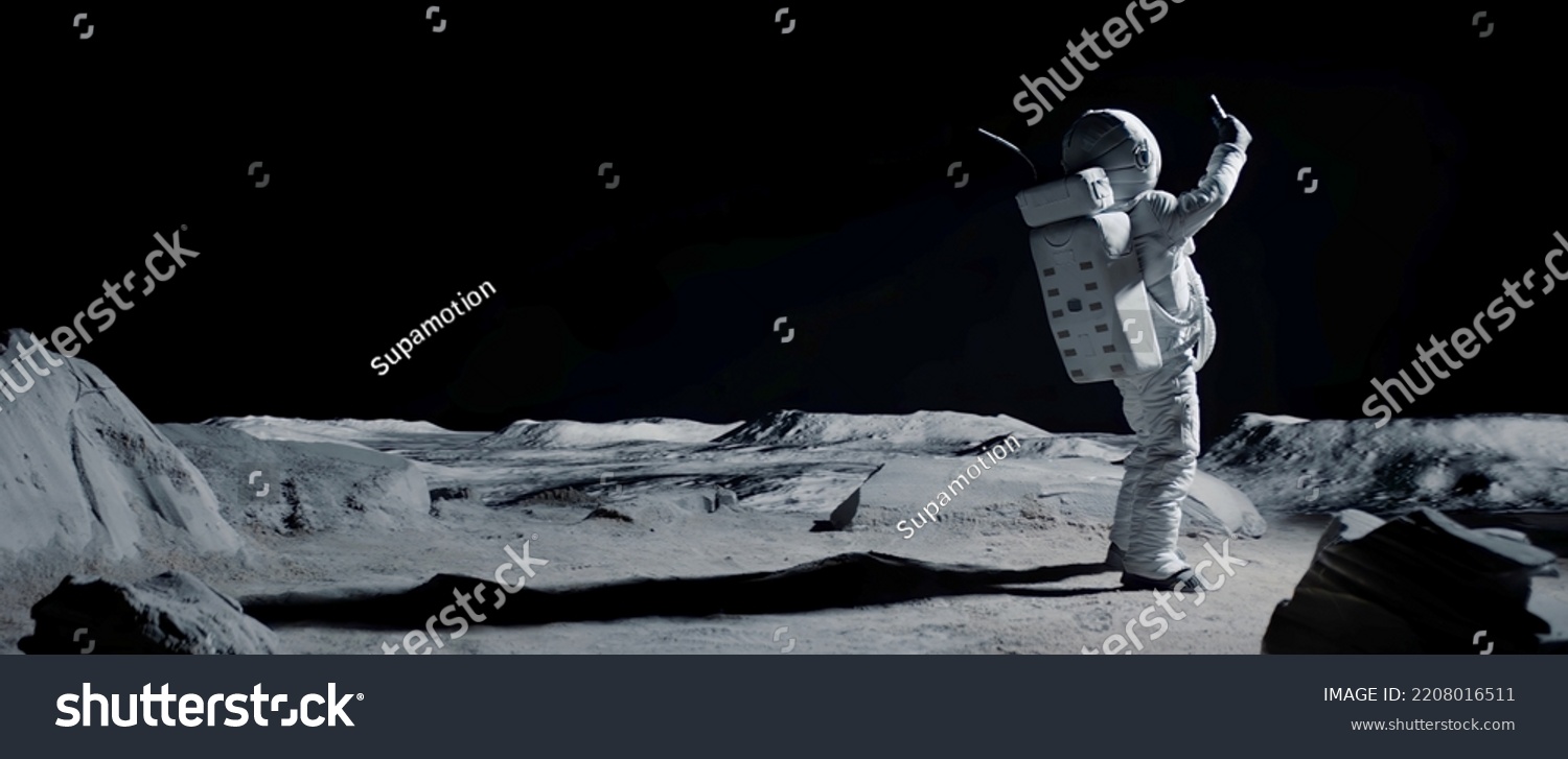 Astronaut searching for cellular or wi-fi signal while walking on Moon ...