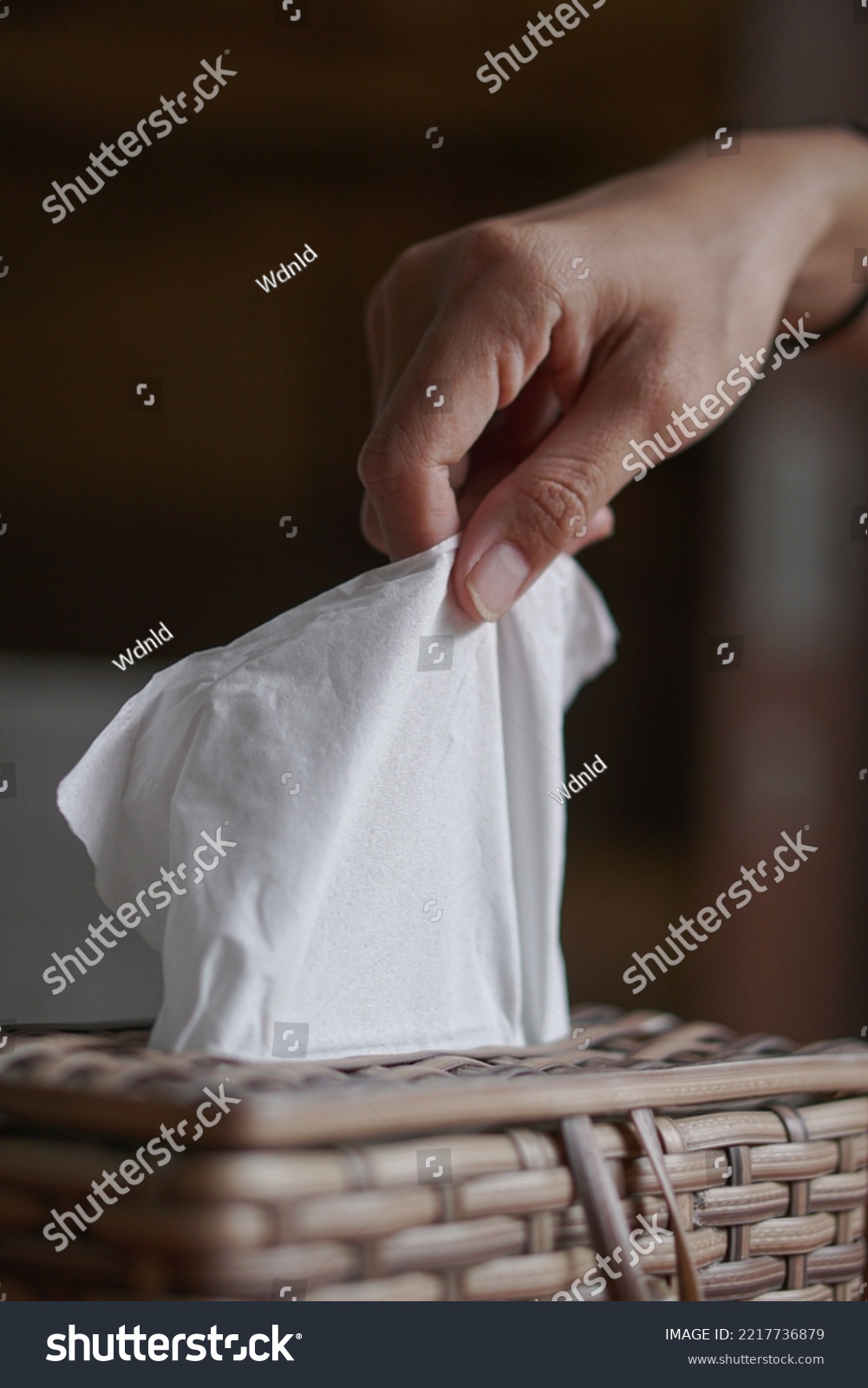 Female hand takes one white paper tissue in wooden container box ...