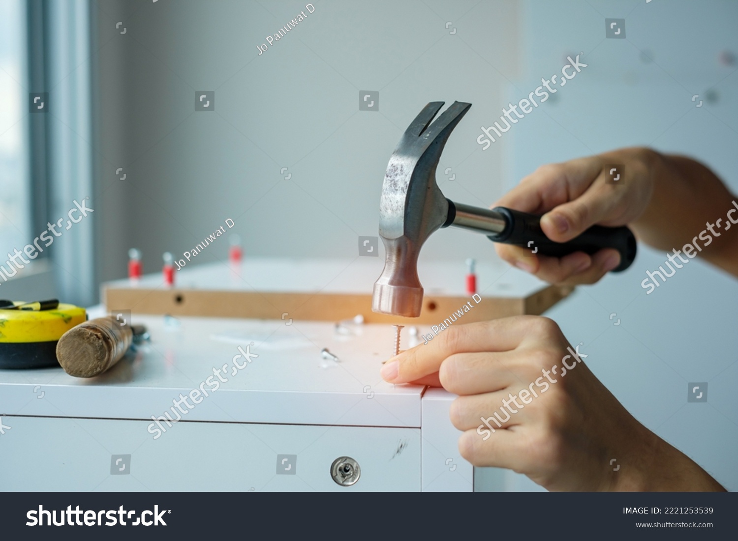 man using hammer hammering a nail into wooden boards assembling or ...