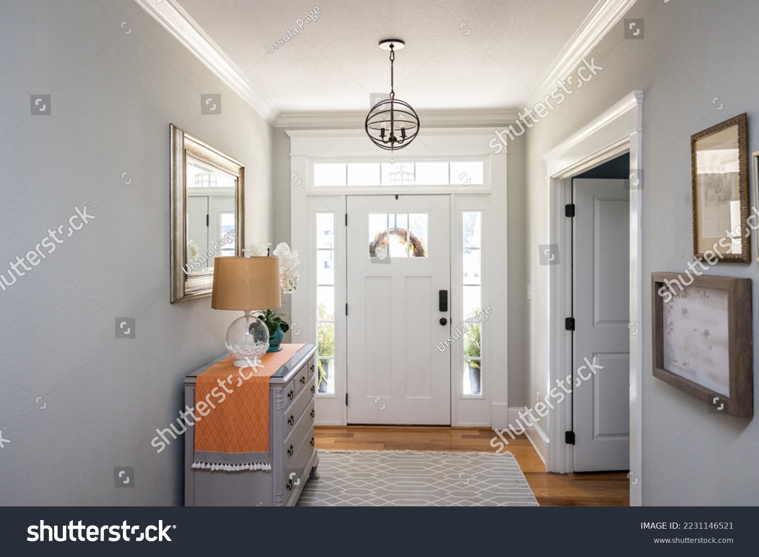 An open large and wide interior front door hallway foyer with transom hanging light fixture ...
