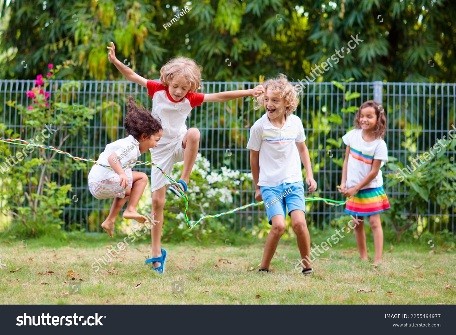 Happy kids play outdoor. Children skipping rope in sunny garden. Summer ...