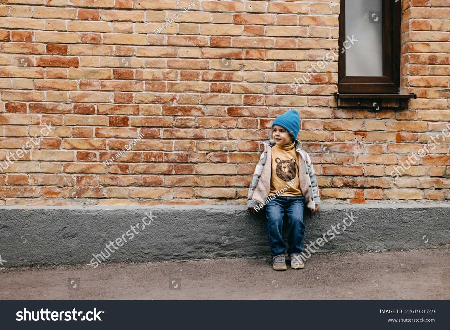 Toddler boy outdoors sitting by a brick wall on city streets._站酷海洛_正版图片 ...