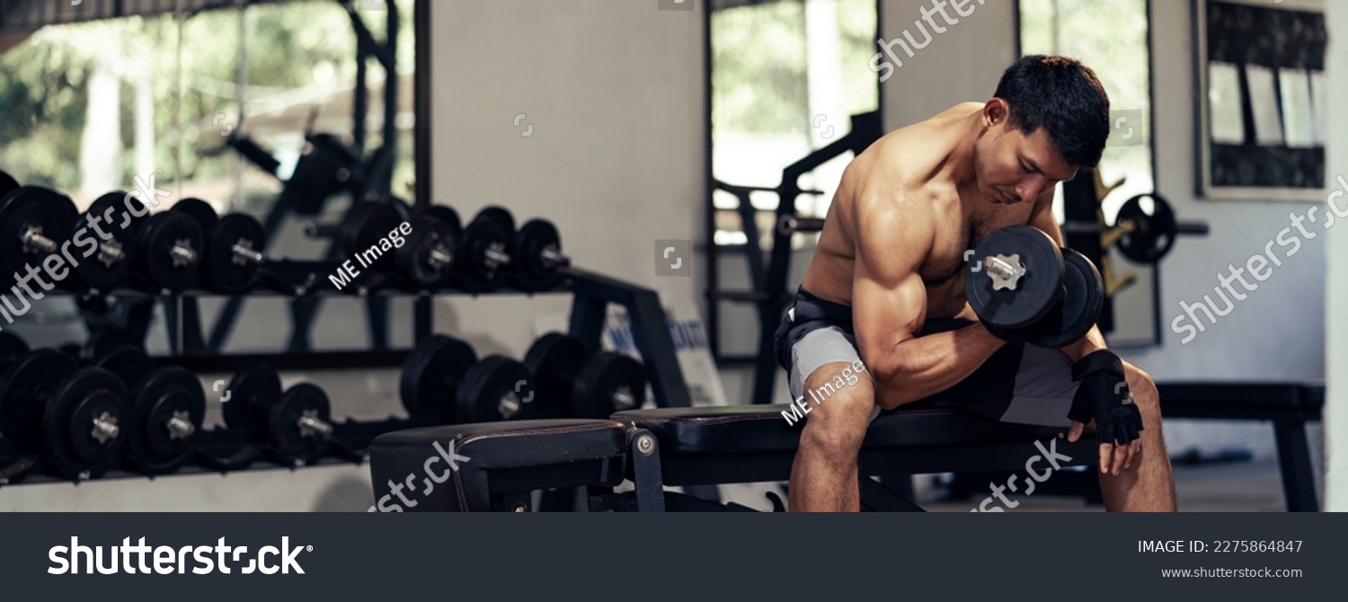 Asian man athletic workout weight training biceps muscles with dumbbell ...