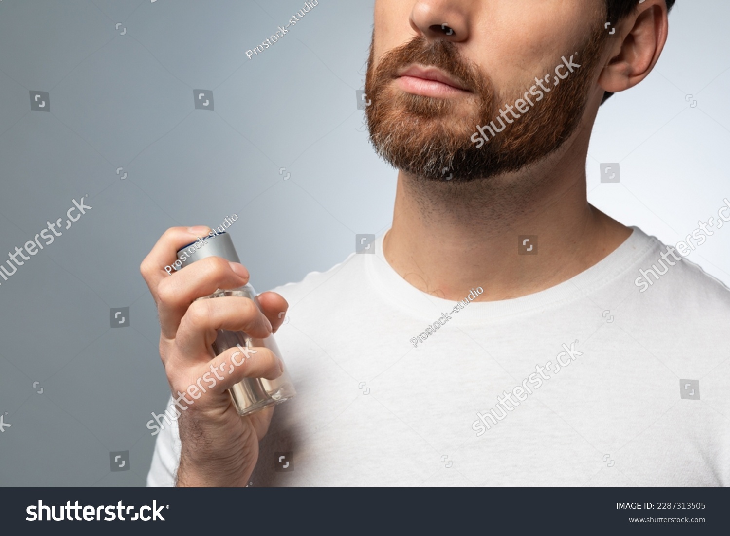 Unrecognizable bearded middle aged man spraying perfume on himself ...