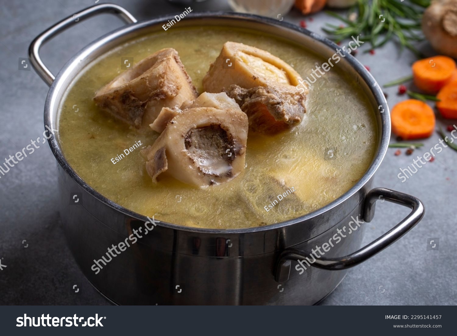 Boiled bone and broth. Homemade beef bone broth is cooked in a pot on ...