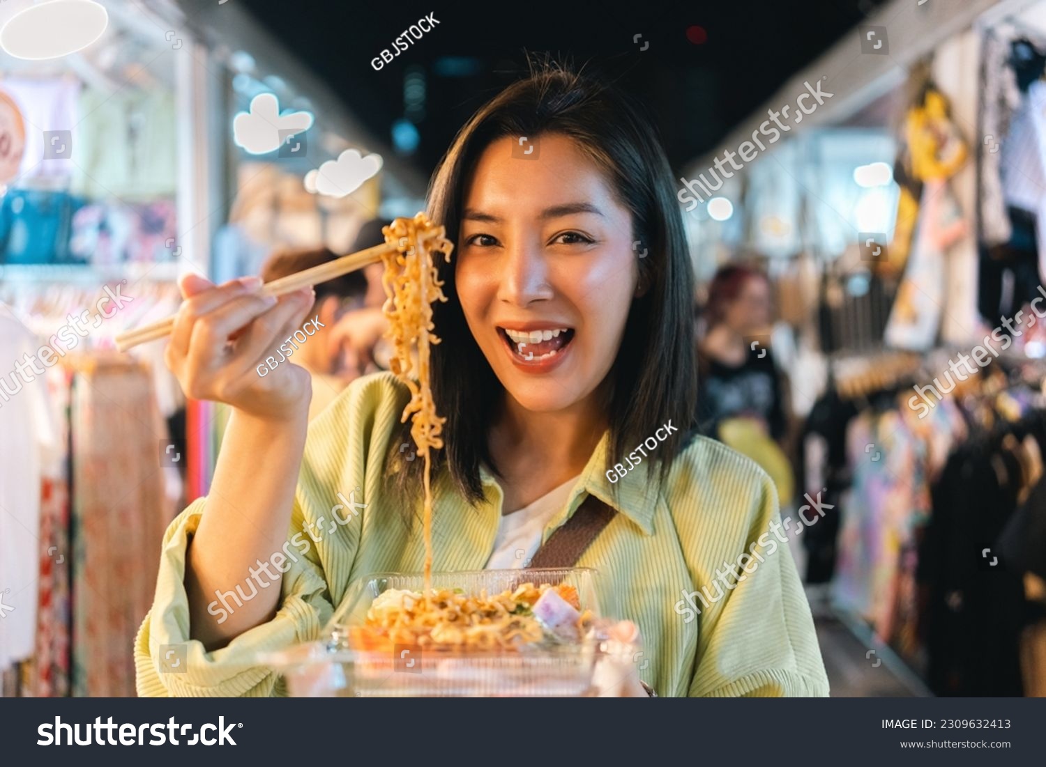 Asian woman enjoy eating noodles street food at night market. Traveler Asian blogger women Happy ...