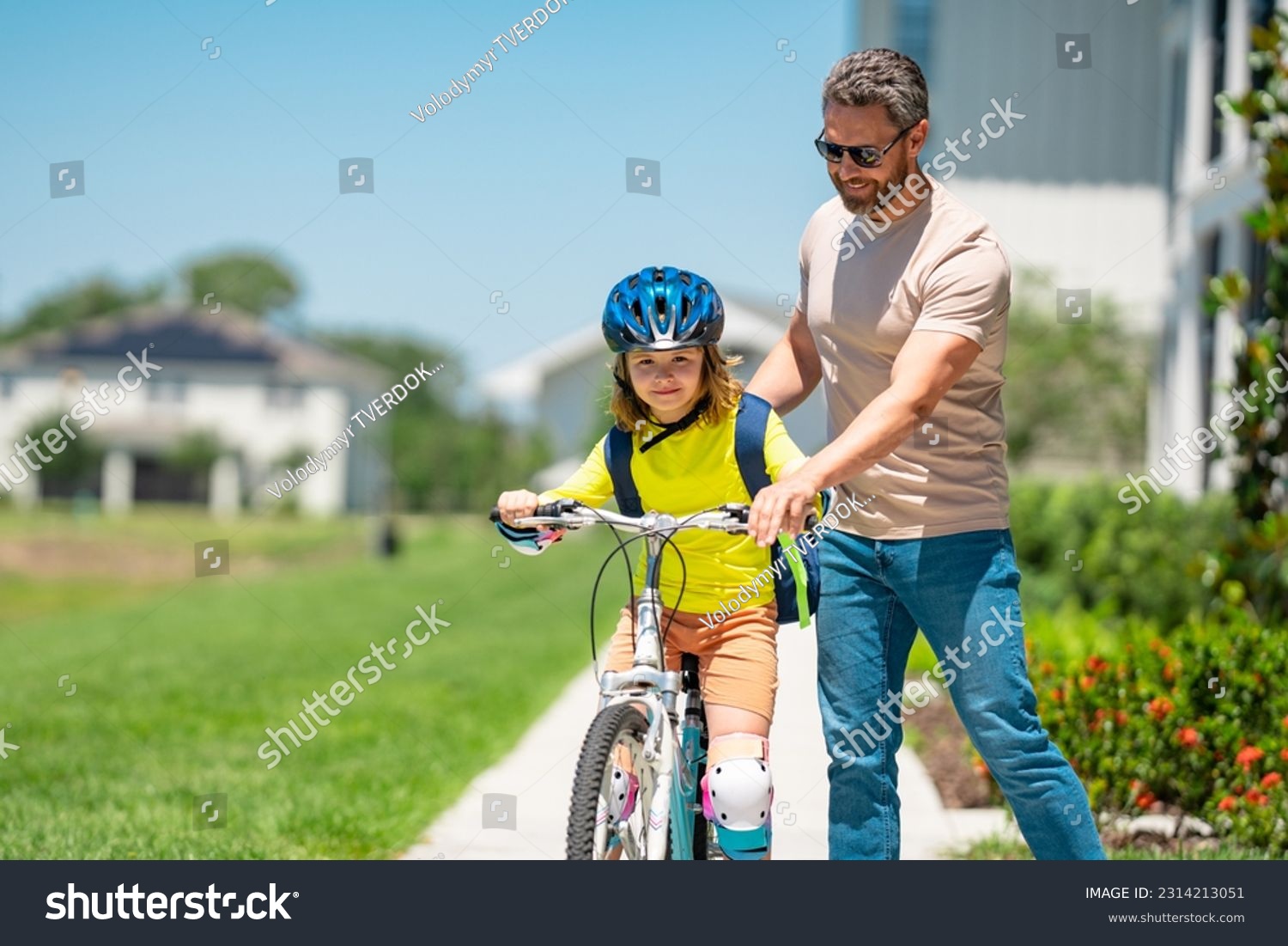 Fathers day. Boy learning to ride a bicycle with his father in park on summer day. Father ...