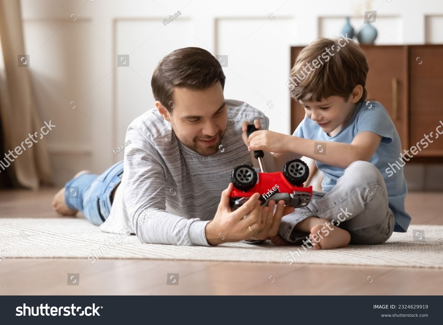 Loving young Caucasian father sit on floor feel playful repair fix toy ...