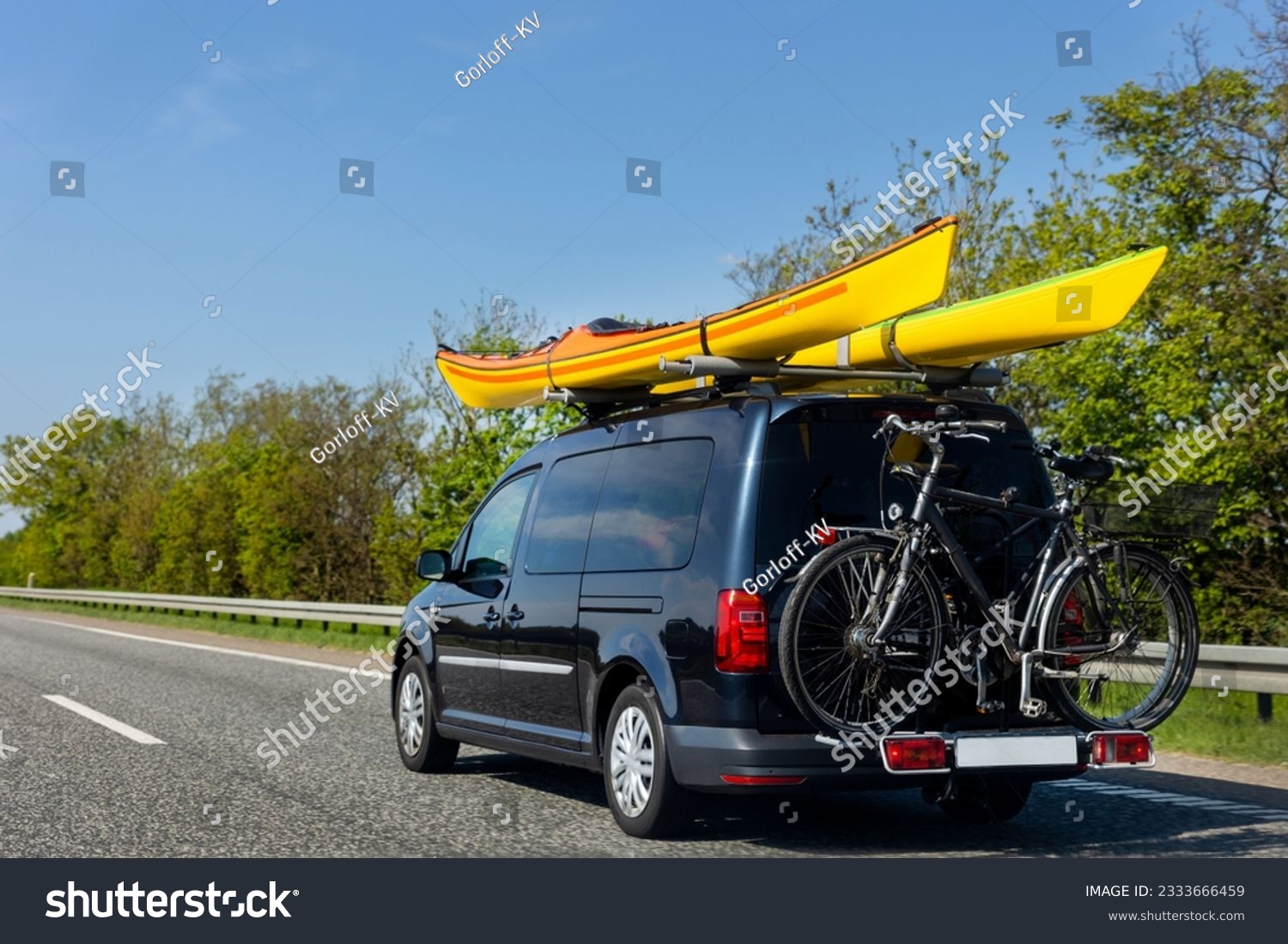 Back view modern black family wagon van car with mounted roof kayak and bike tail carrier ...