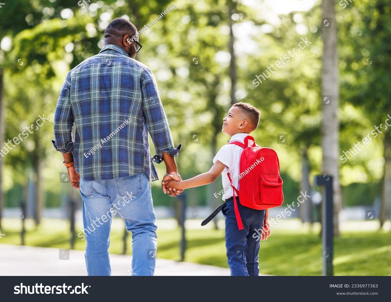 On way to school. Ethnic son schoolboy with backpack holding hand of ...