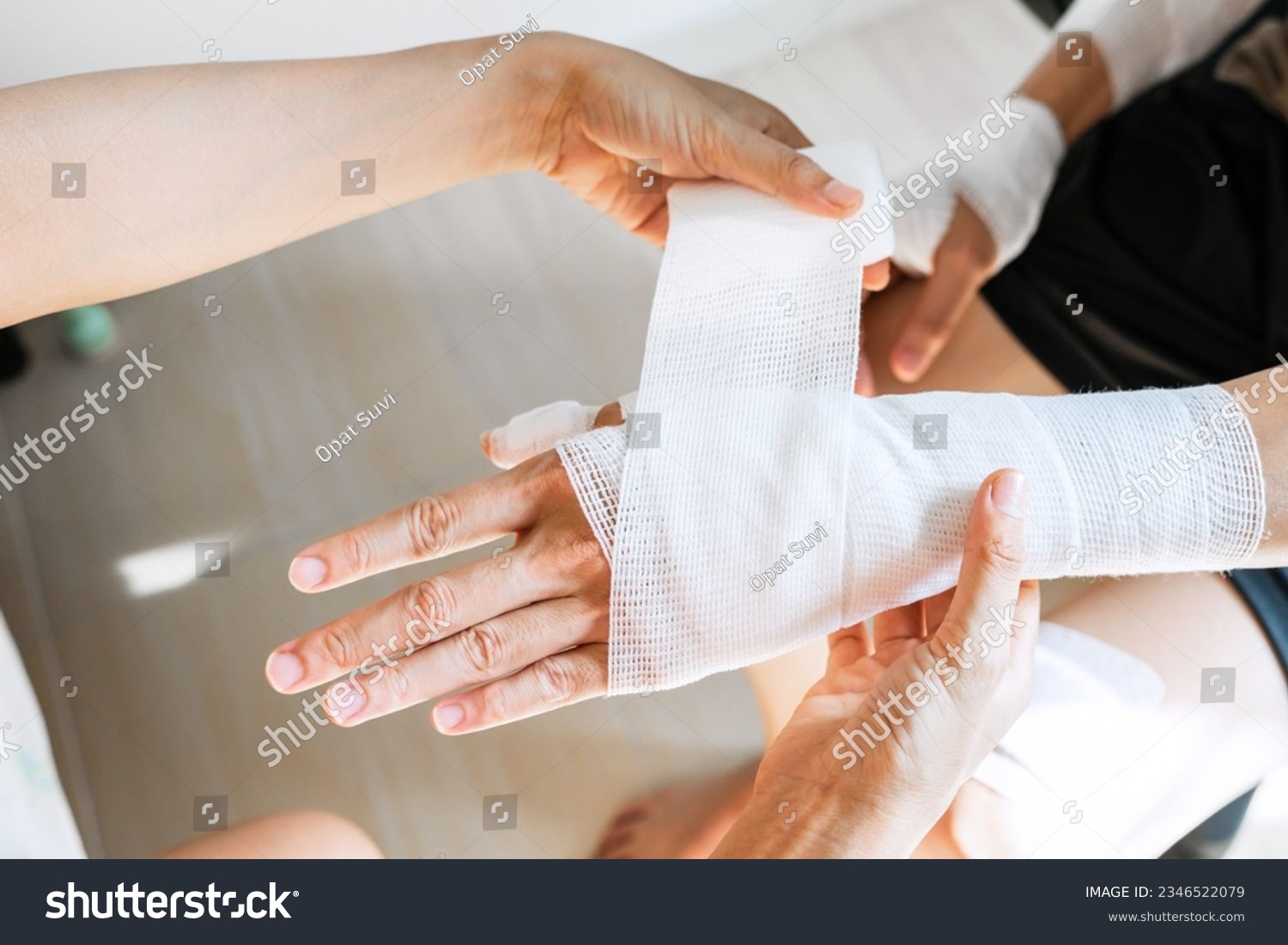 Sister wrapping her brother wrist and arm with bandage around injured ...