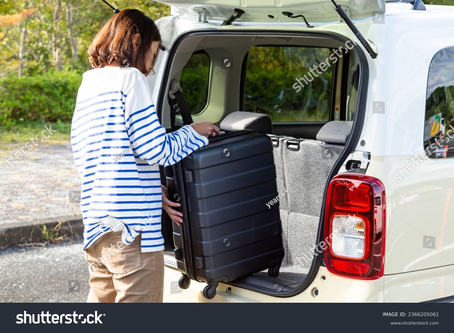 A woman carrying a carry case to the car._站酷海洛_正版图片_视频_字体_音乐素材交易平台_站酷旗下品牌