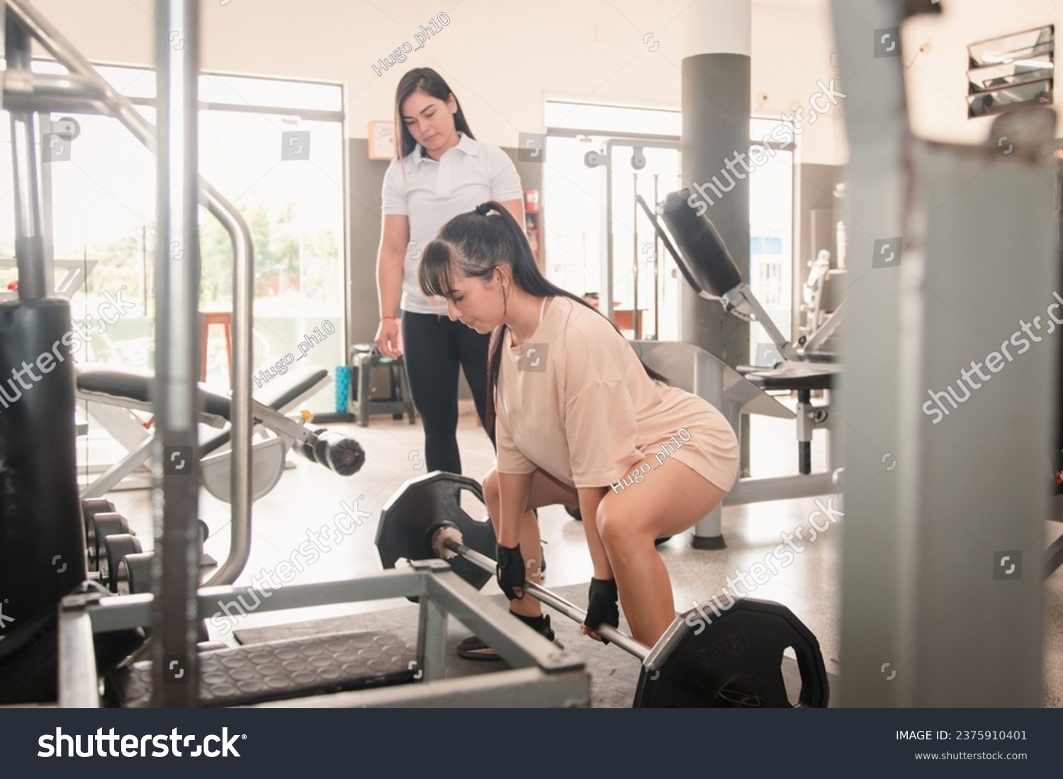 Trainer looking at a fitness girl doing a barbell squat in the gym._站酷海洛_正版图片_视频_字体_音乐素材交易平台_站酷旗下品牌