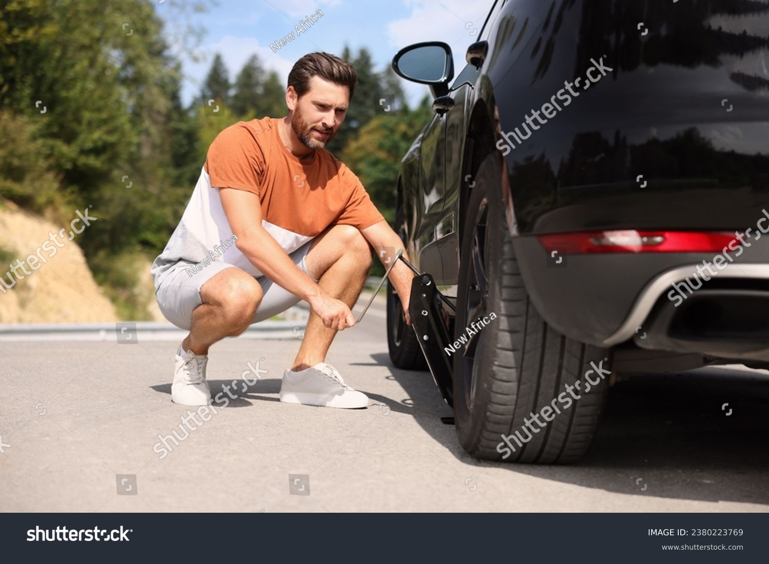 Man lifting car to change wheel on roadside outdoors_站酷海洛_正版图片_视频_字体_音乐 ...