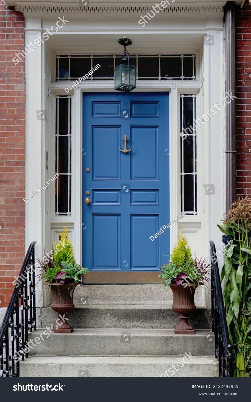 A vibrant blue front door features sidelight windows on each side and a transom window above ...