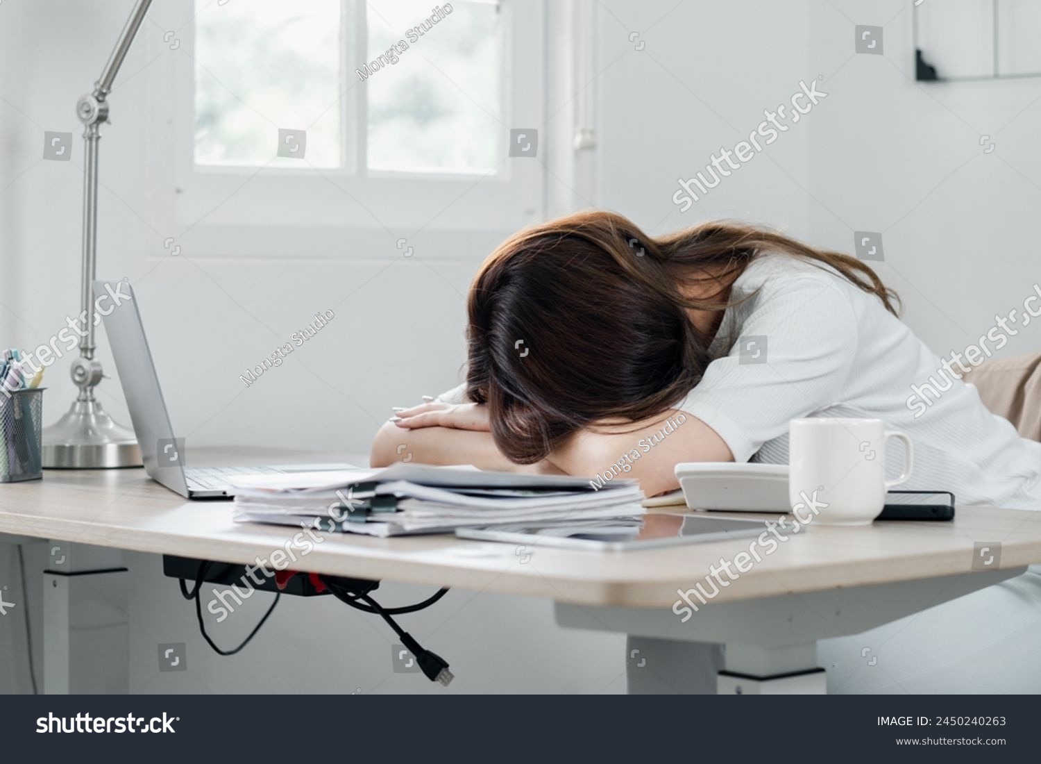 Exhausted professional takes a quick power nap at her desk amidst a ...