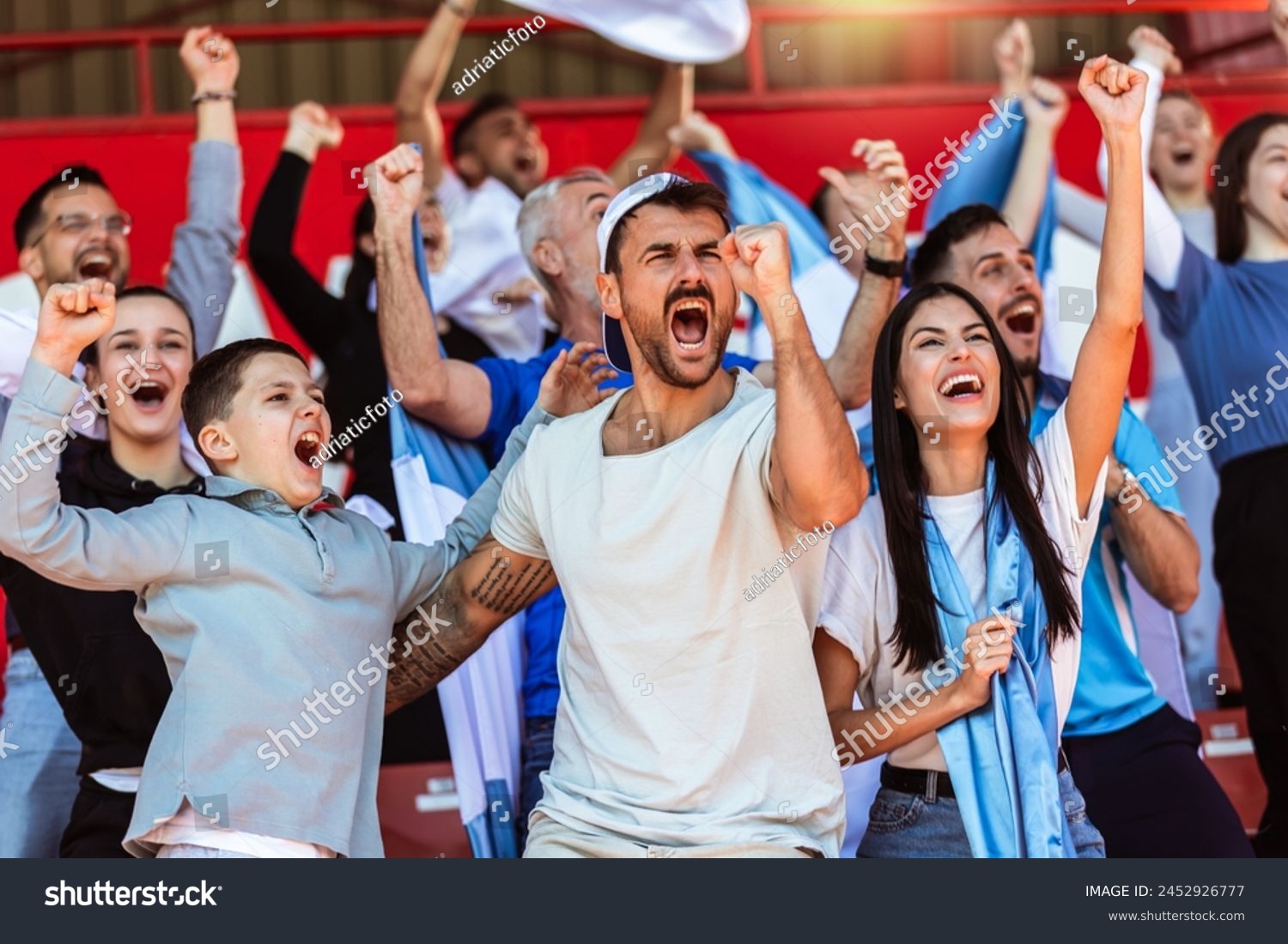 Sport fans cheering at the game on stadium. Wearing blue and white ...