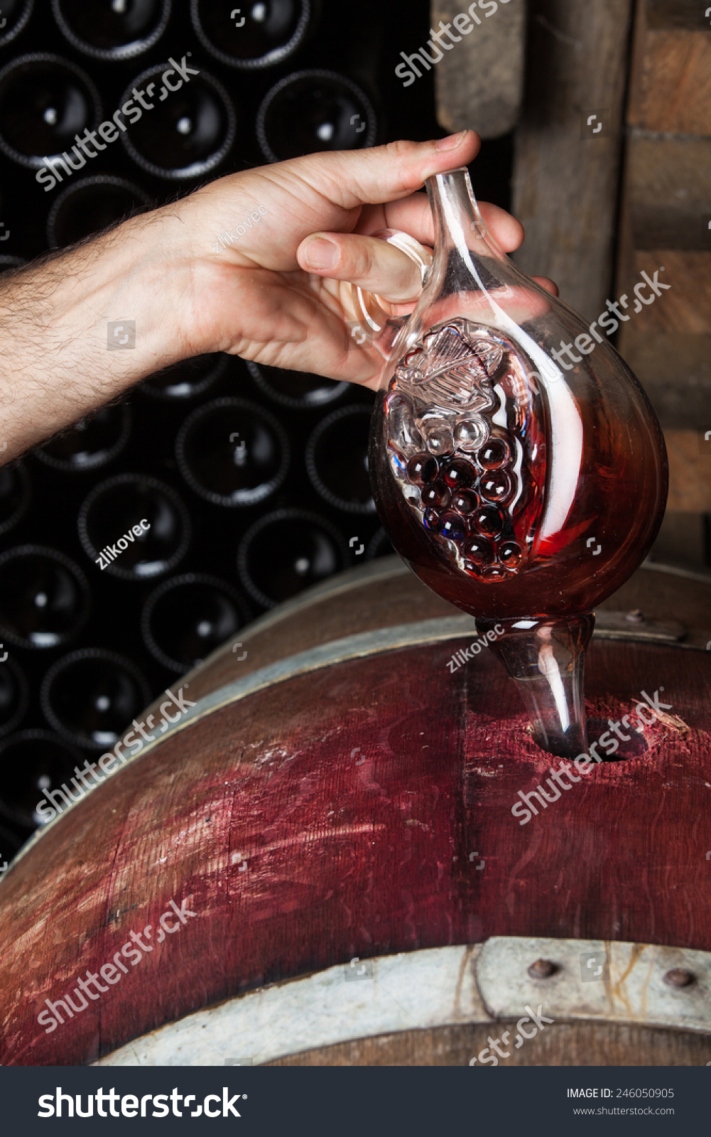 Sommelier sampling red wine from oak barrel bottles in the background_站 ...