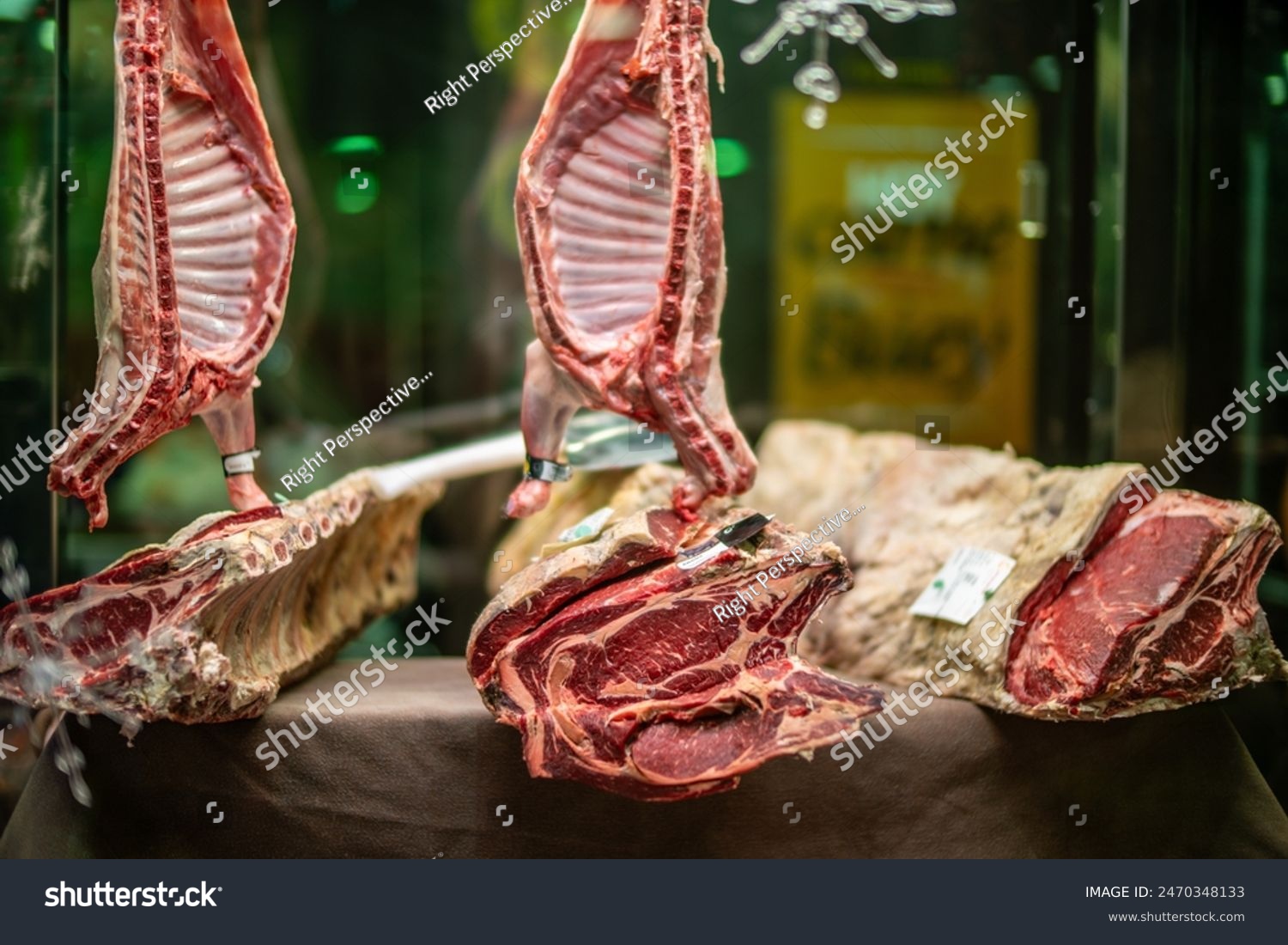Two lamb carcasses and a beef rib hang in a Seville butcher shop showcasing the premium quality ...