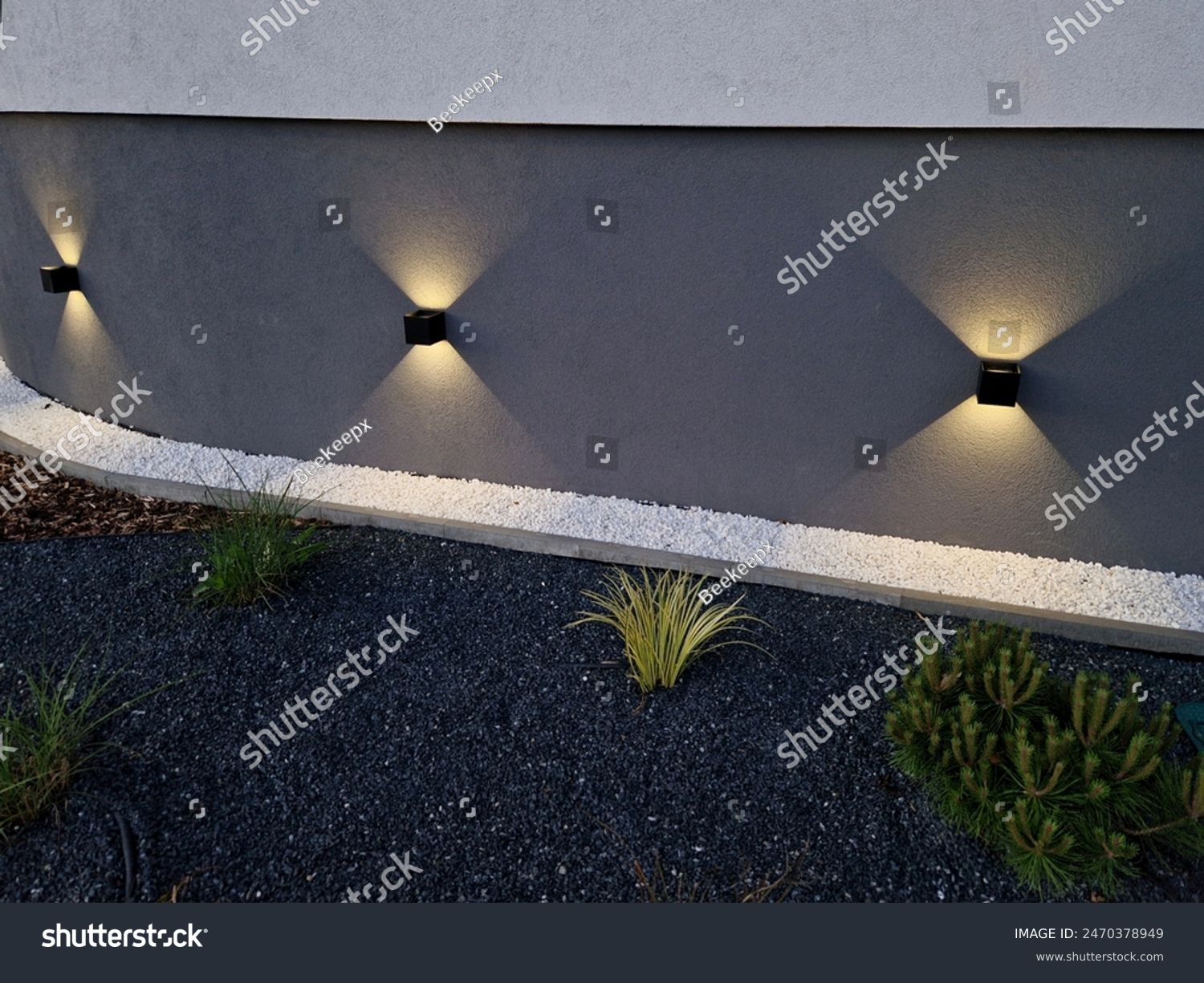 the spot wall light illuminates the wall of the facade of the house in ...