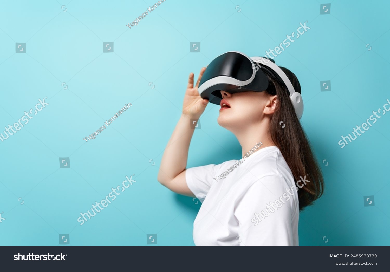 Metaverse technology concept. Woman with VR virtual reality goggles on light blue wall ...