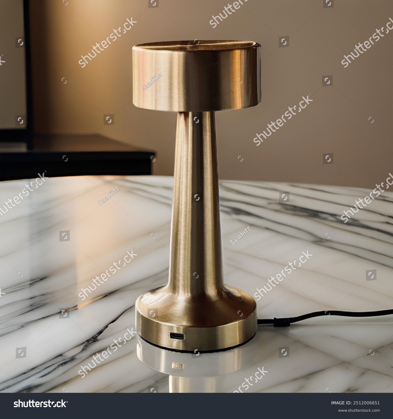 Sleek golden table lamp with a modern design placed on a reflective ...