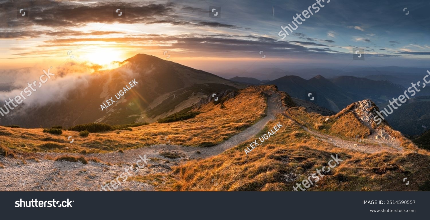 Beautiful sunset on mountain with trail leading up side. Trail is ...