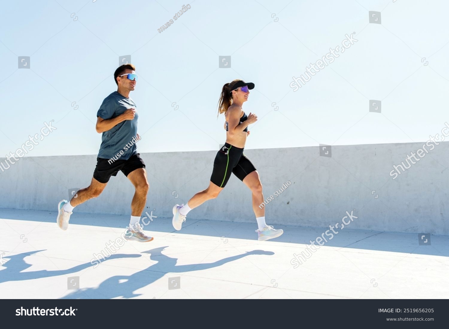 Two people run side by side on a bright sunny morning enjoying their ...