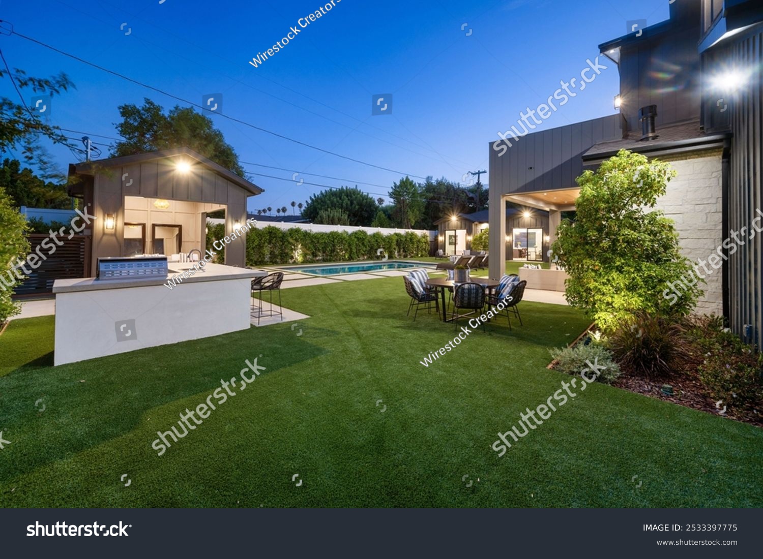Modern backyard with outdoor kitchen seating area and swimming pool at dusk._站酷海洛_正版图片_视频_字体_音乐 ...