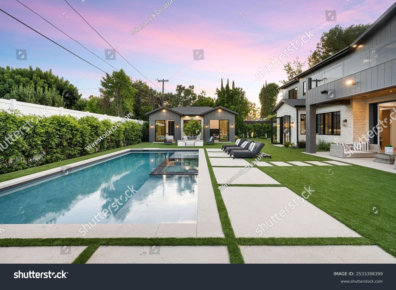 Modern backyard with a swimming pool lounge chairs and a guest house under a beautiful sunset ...