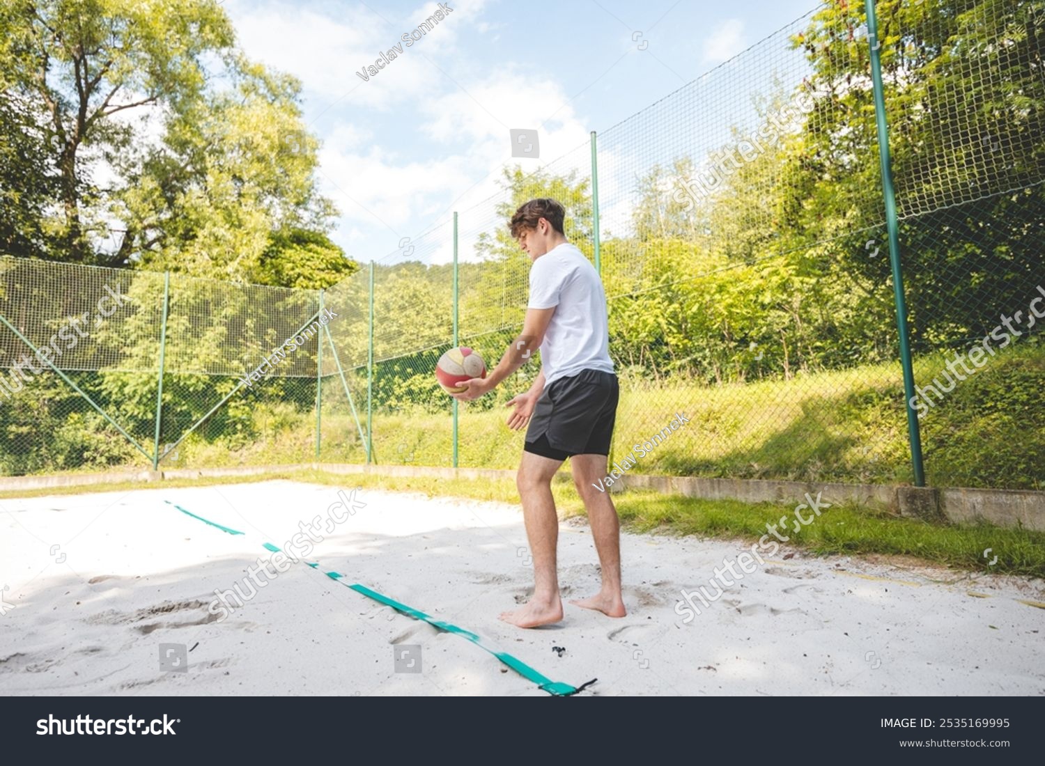 Volleyball player practicing a bump pass on a sand court focusing on technique and control ...