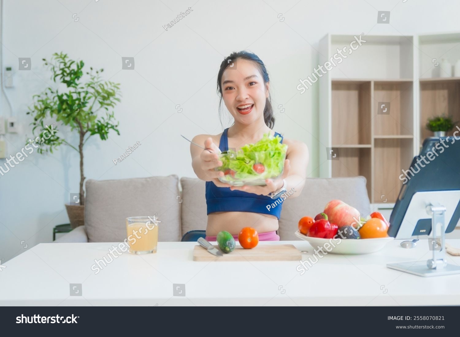 A young Asian housewife enjoys a healthy lifestyle at home balancing fitness routines with ...