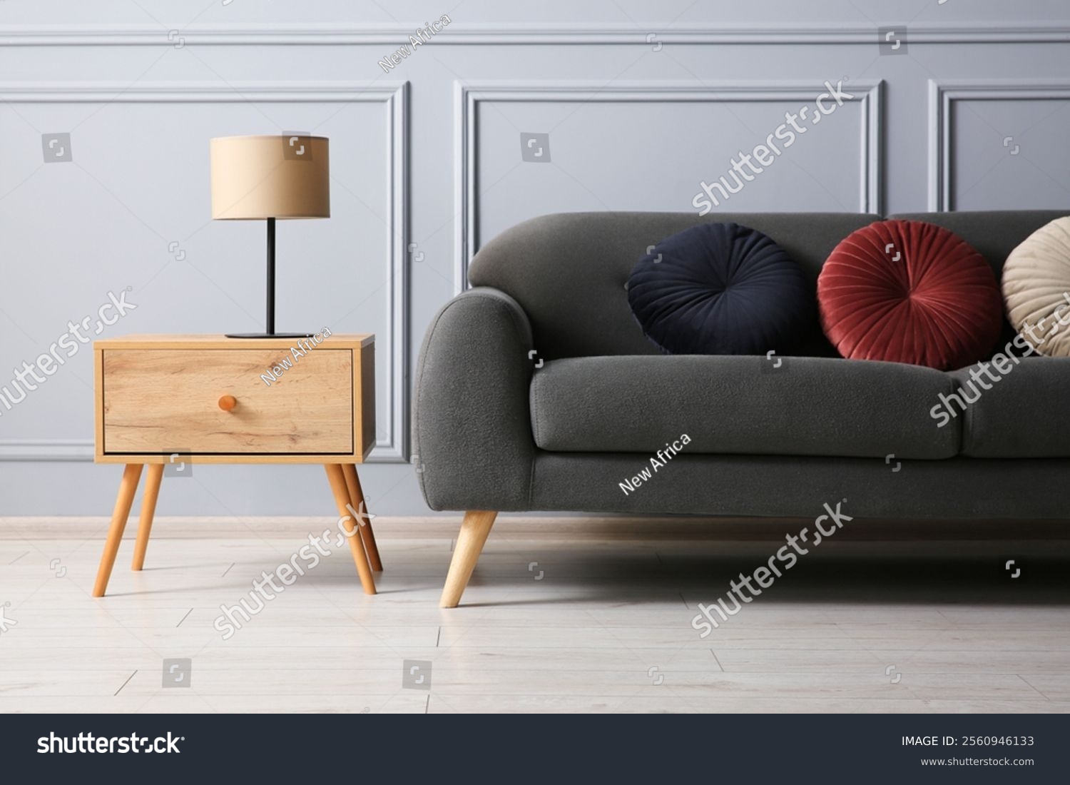 Stylish sofa with cushions and lamp on side table near grey wall_站酷海洛_正版图片_视频_字体_音乐素材交易平台_站酷旗下品牌