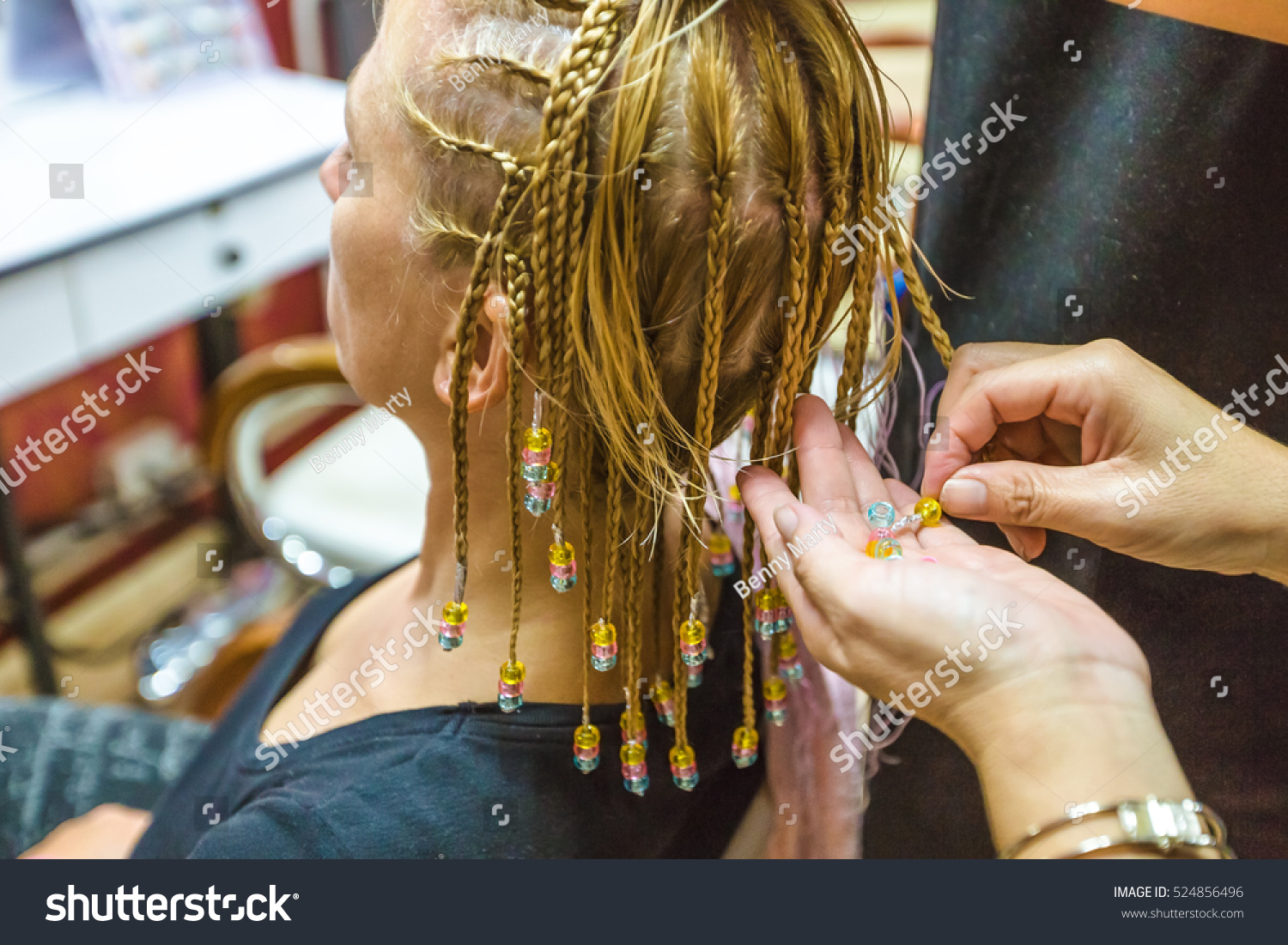Close up of the hands of a beautician while doing braids to a young ...