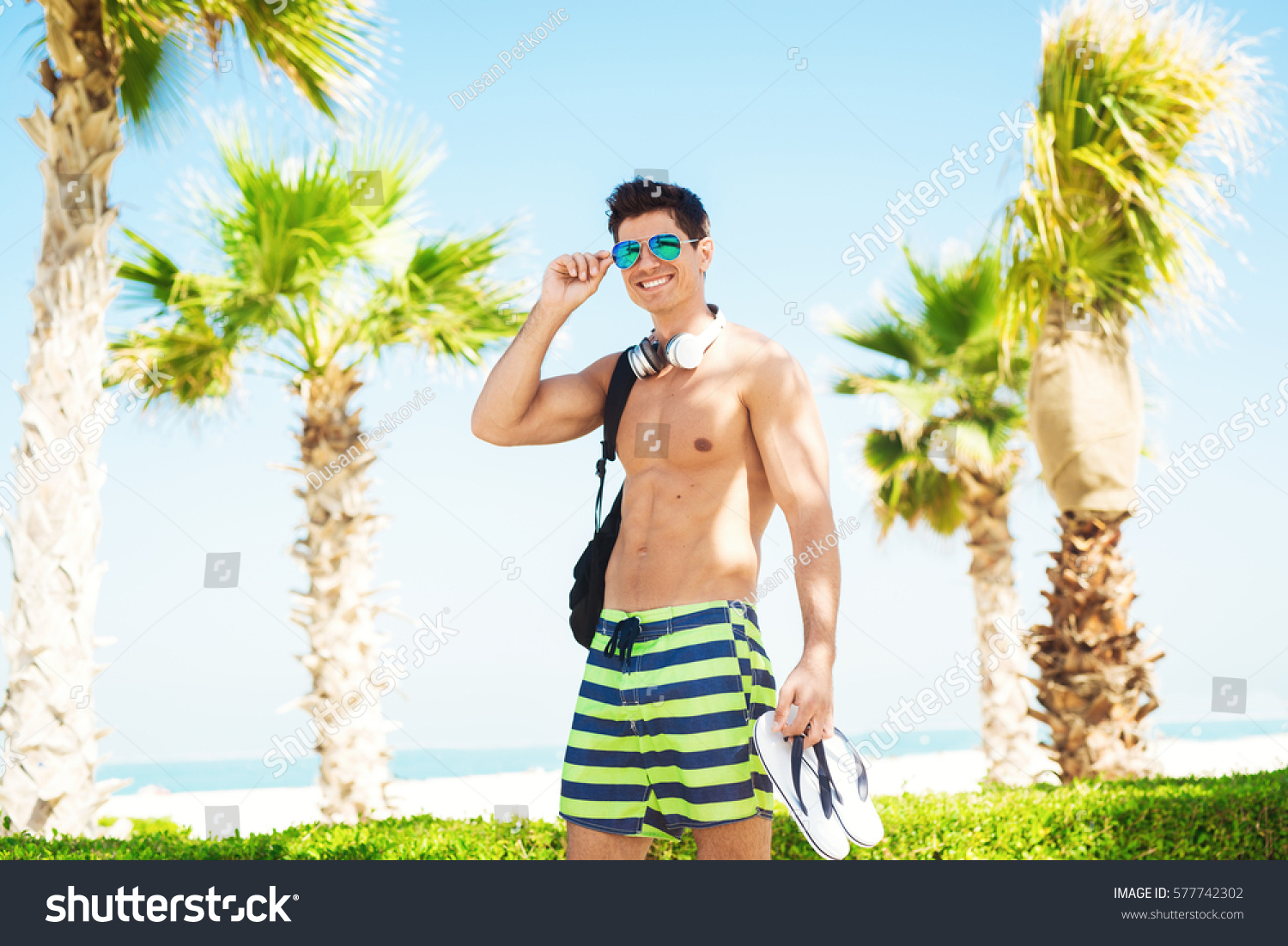 Handsome guy in cool beach outfit smiling walking down seaside to bright beach party_站酷海洛_正版图片 ...
