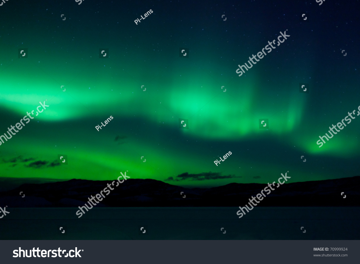 Green northern lights (aurora borealis) substorm above silhouette of ...