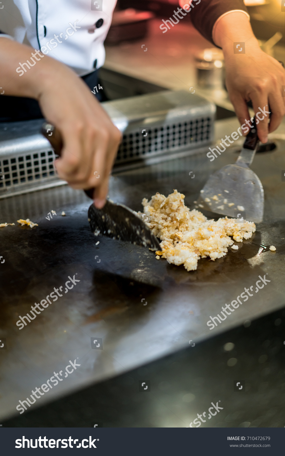 Hand of Chef cooking garlic fried rice on hot pan in front of customers. Japanese Tepanyaki ...