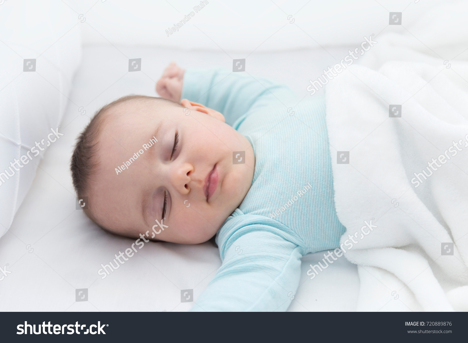 Baby sleeping with open arms and without pacifier in a cradle. Light ...