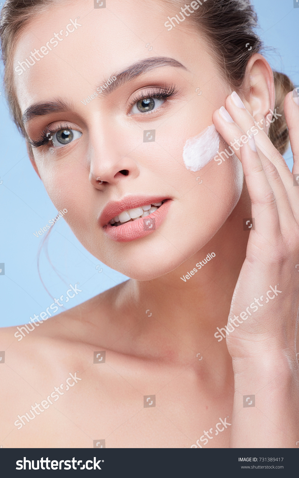 Beauty concept beauty portrait of young woman applying cream on face ...