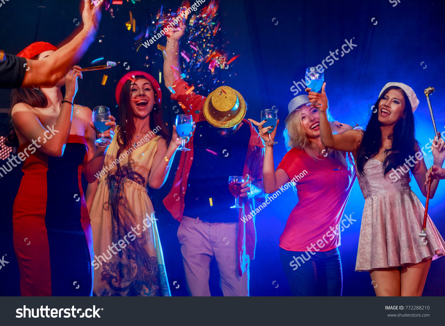Group of young people having fun dancing and throwing colorful confetti ...